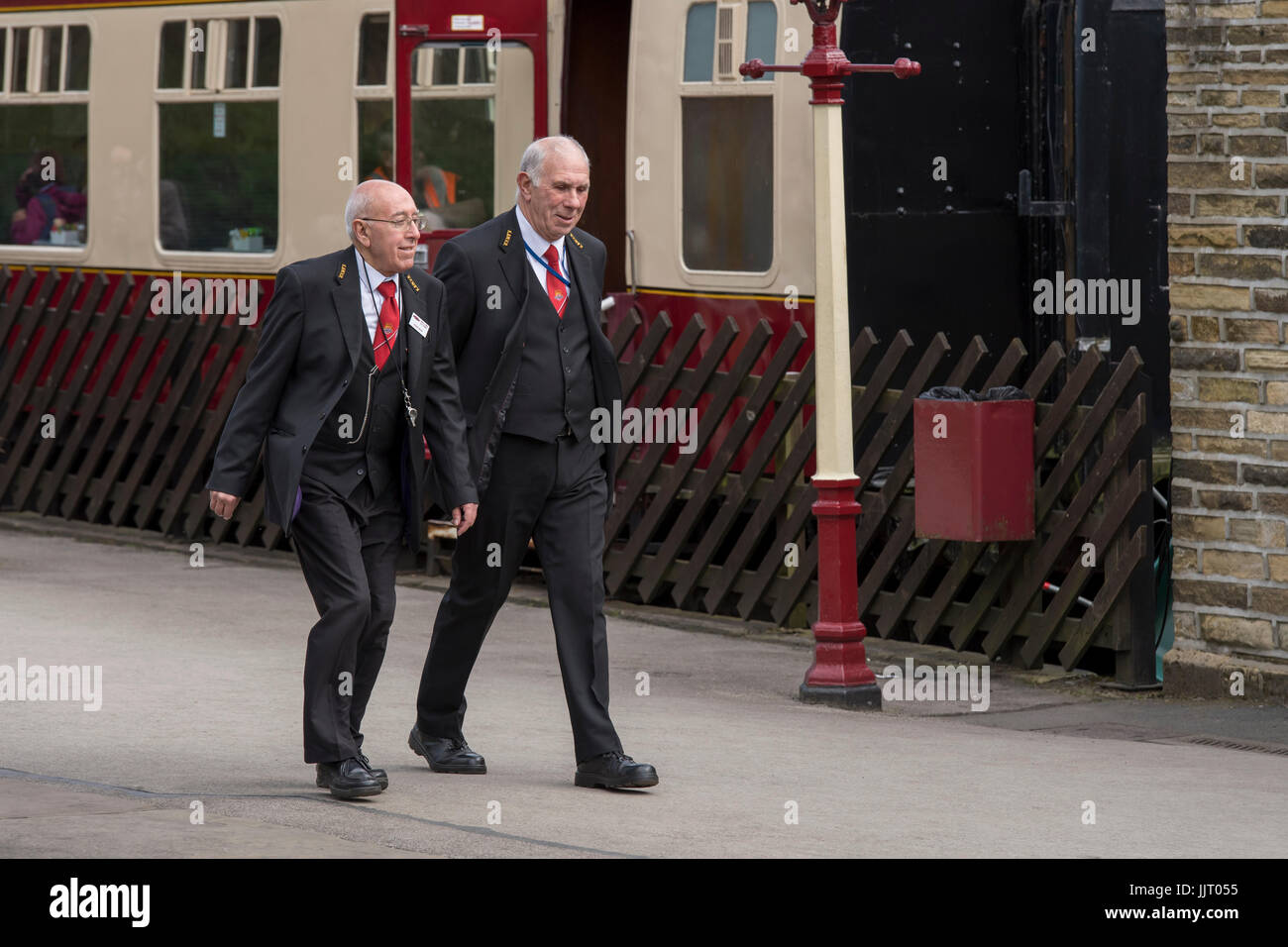 Two male train guards in uniform, walking together along platform ...