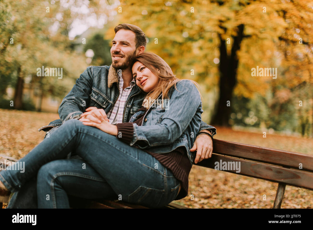 Young loving couple sitting on the bench in the autumn park Stock Photo ...