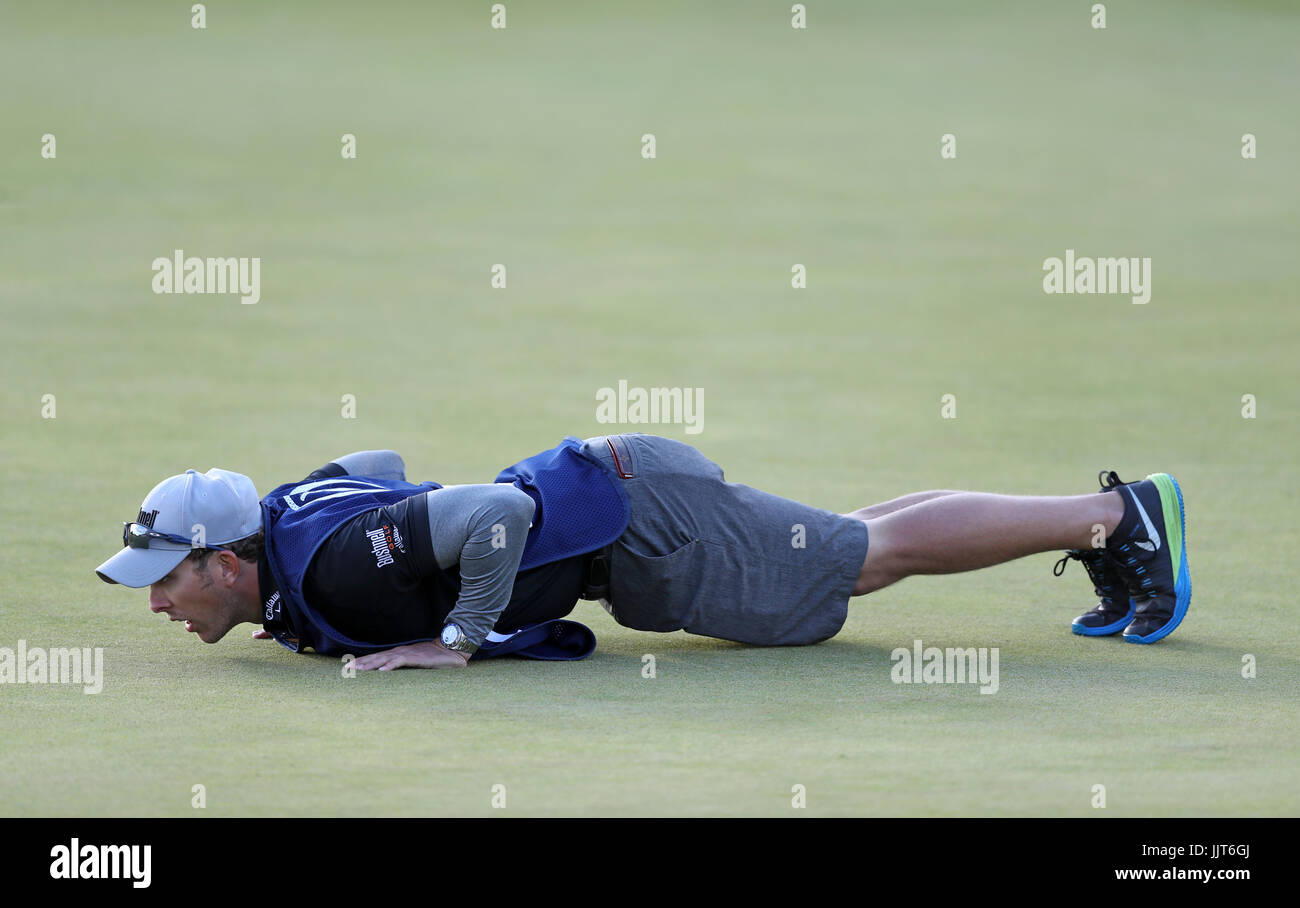 USA's Patrick Reed's caddie lines up his putt on the 18th during day ...