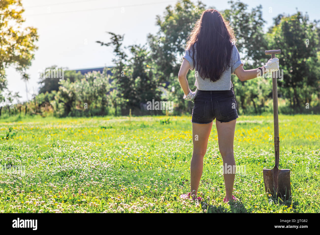 Back shot of a woman standing with a shovel looking at a lawn Stock ...