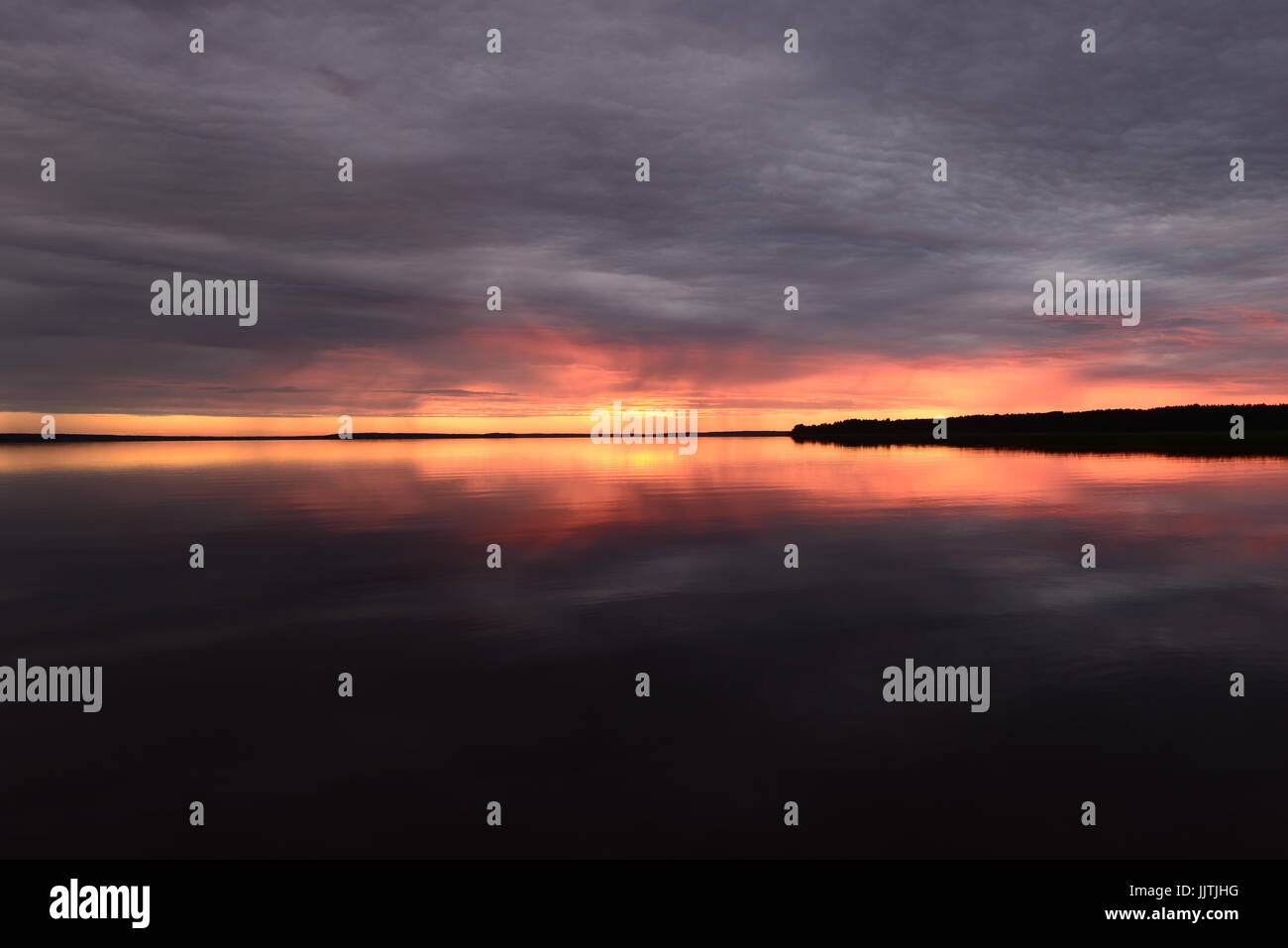 Sunset light up to the horizon line above the water surface of the lake ...