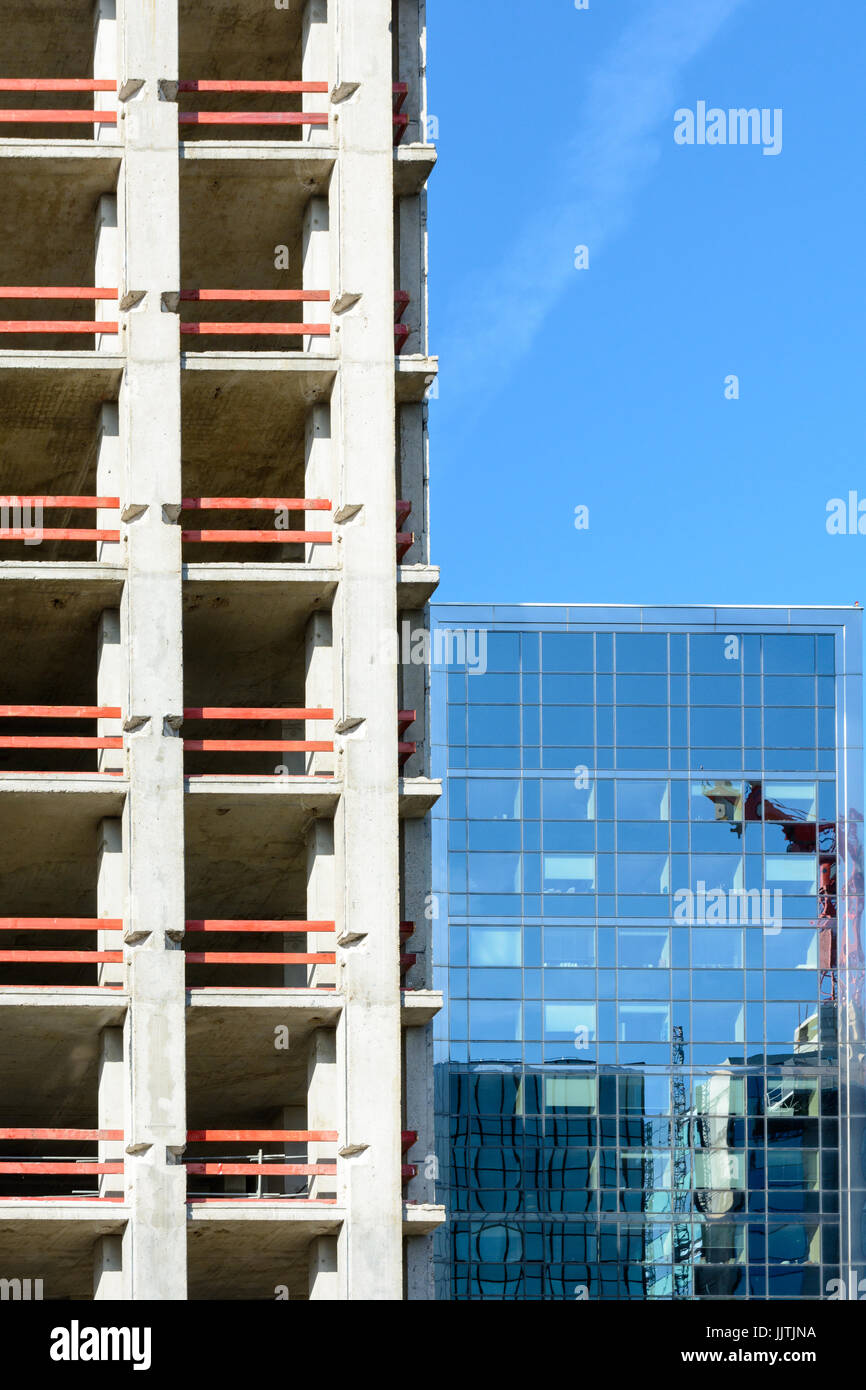 Front view of a concrete building under construction next to a glass ...