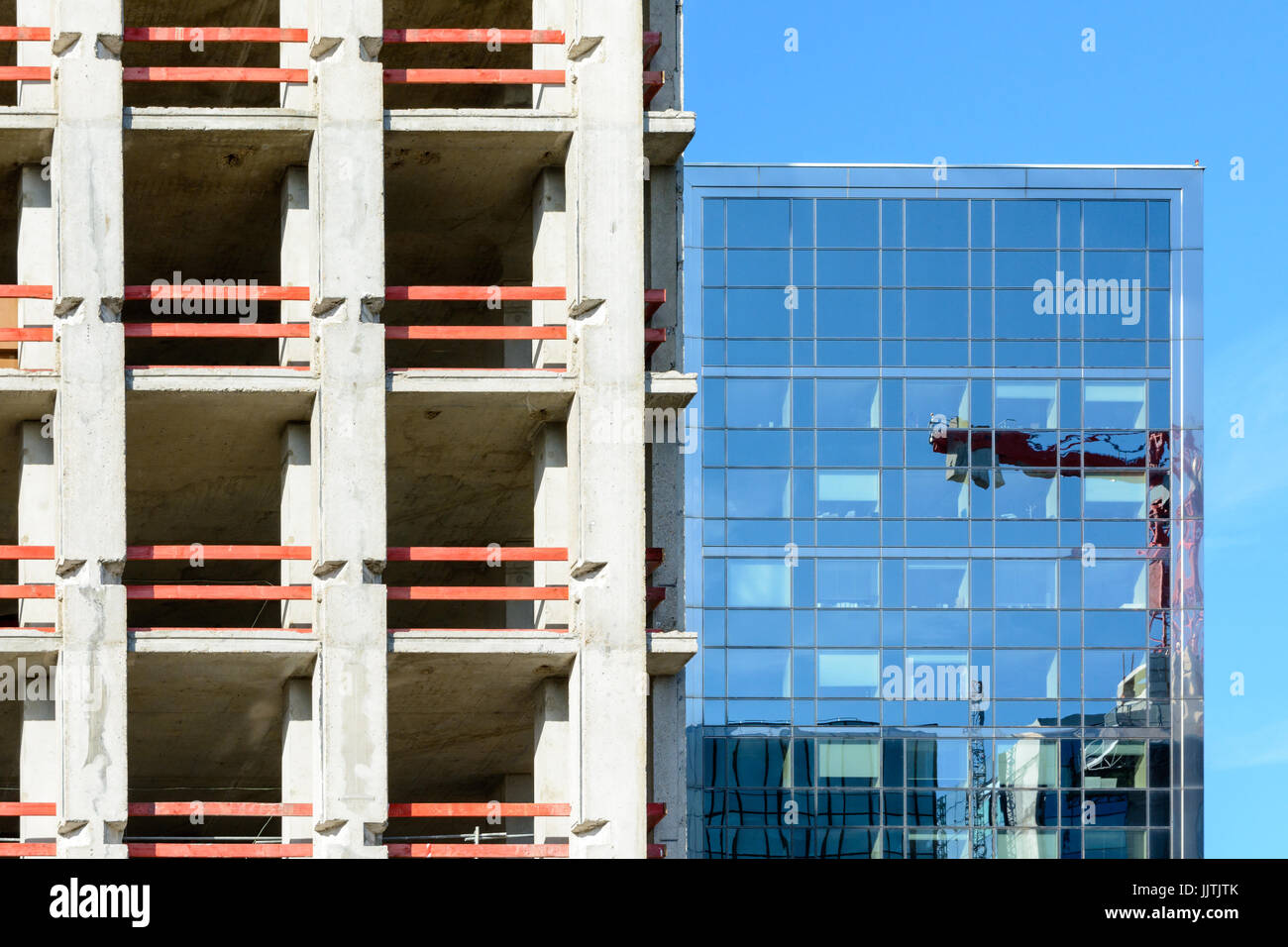Front view of a concrete building under construction next to a glass ...