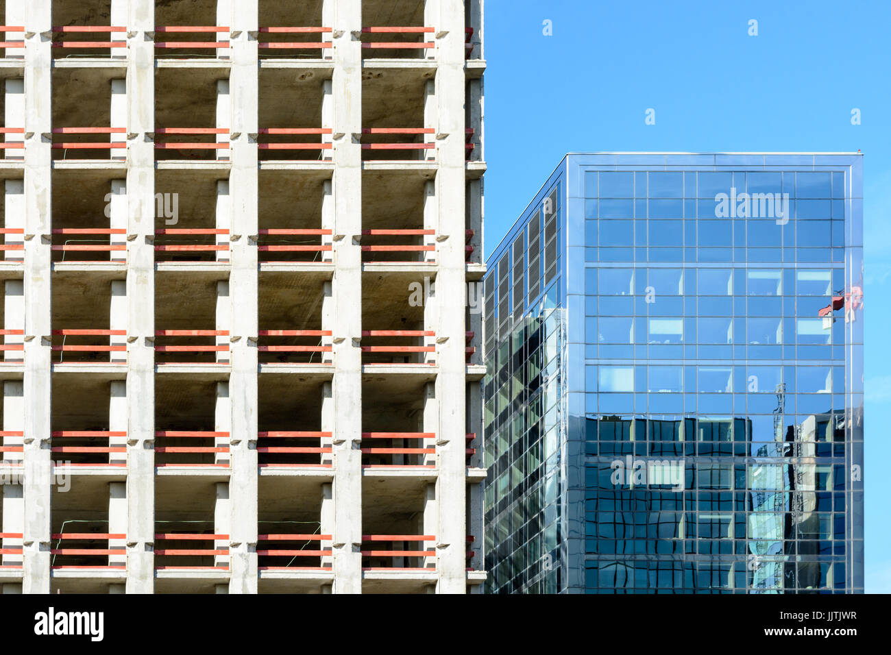 Front view of a concrete building under construction next to a glass ...