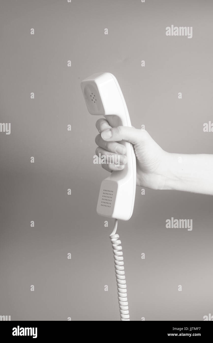 Hand holding white telephone tube on gray background Stock Photo - Alamy