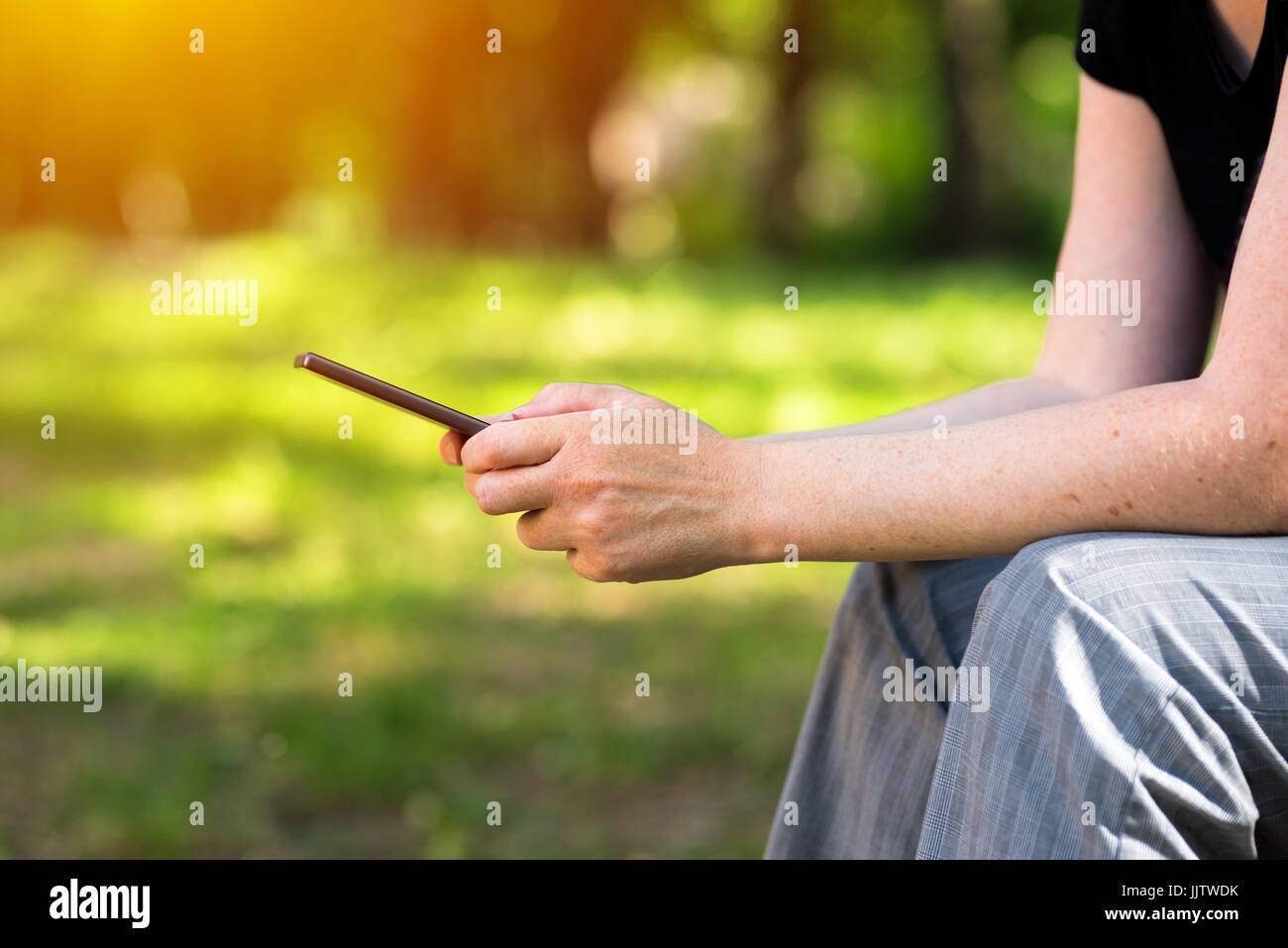 Woman texting on mobile phone while sitting on the park bench Stock ...