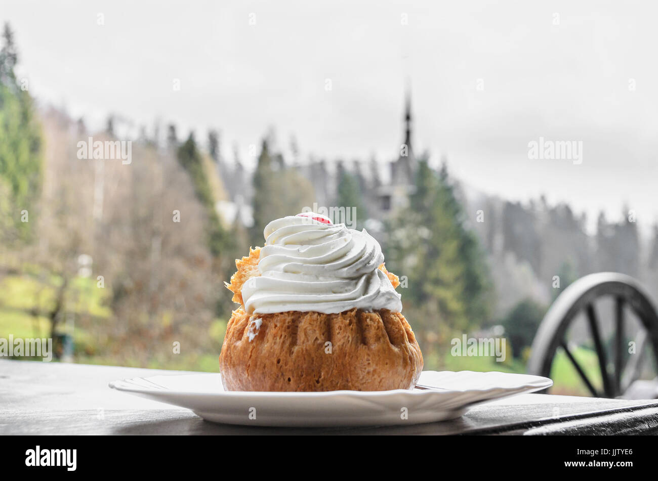 Savarin cake with cream and syrup, white plate, outdoor background ...