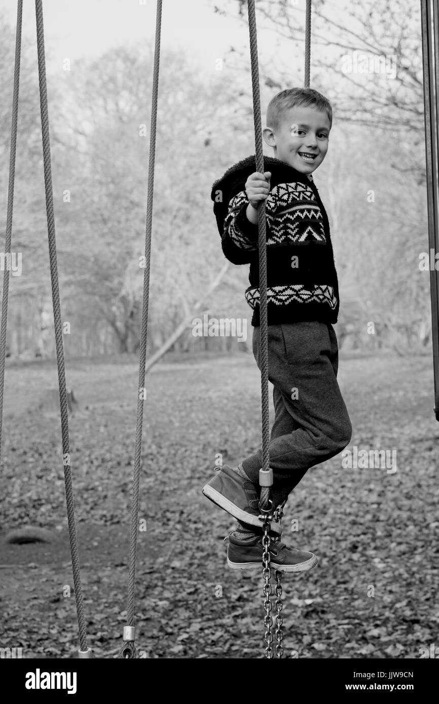 Boy playing on rope/chain ladder in playground Stock Photo - Alamy