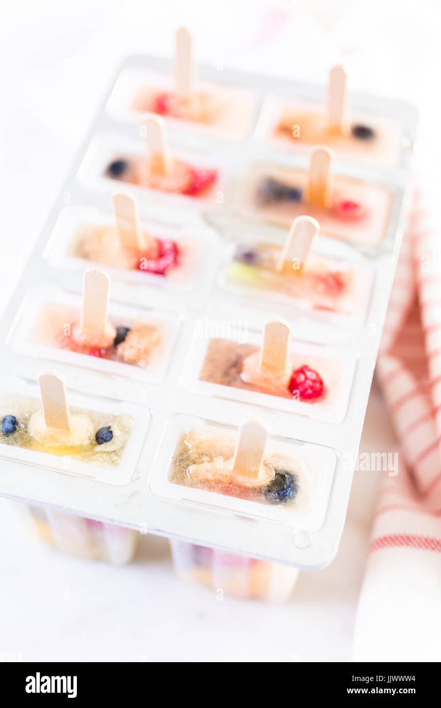 Making homemade fresh fruit popsicles with apple juice in frozn ice pop ...