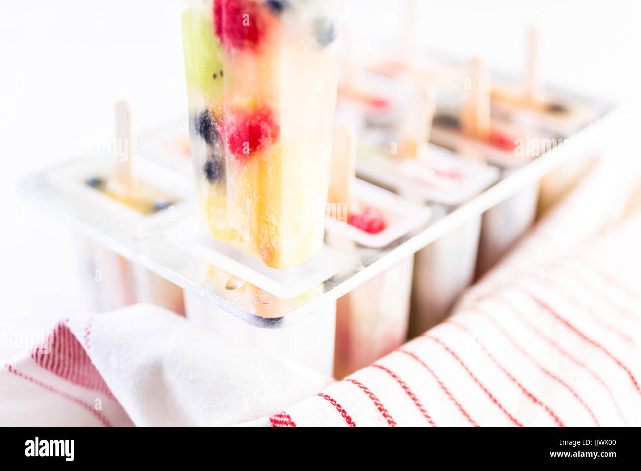 Making homemade fresh fruit popsicles with apple juice in frozn ice pop ...