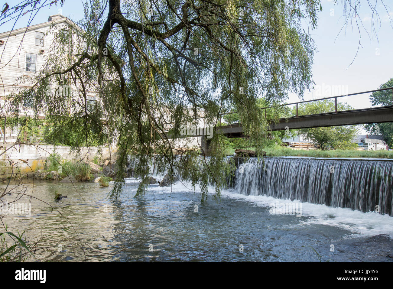 Rustic wooden mill on banks of stream with waterfall Stock Photo - Alamy