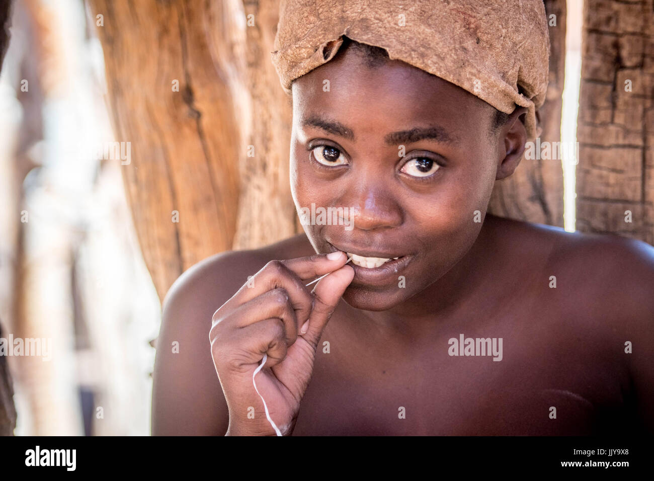 Damara woman using her teeth and fingers to thread a button at the ...