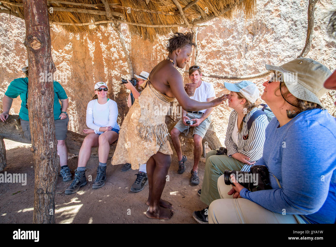 Damara woman painting a tourist's face at the Damara Living Museum in ...