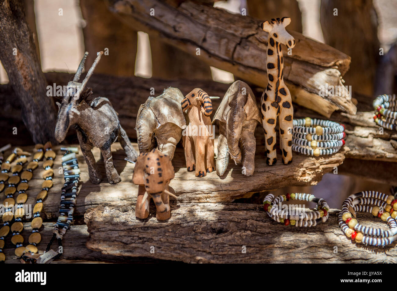 Hand-carved animal figurines, necklaces, and bracelets are lined up at ...