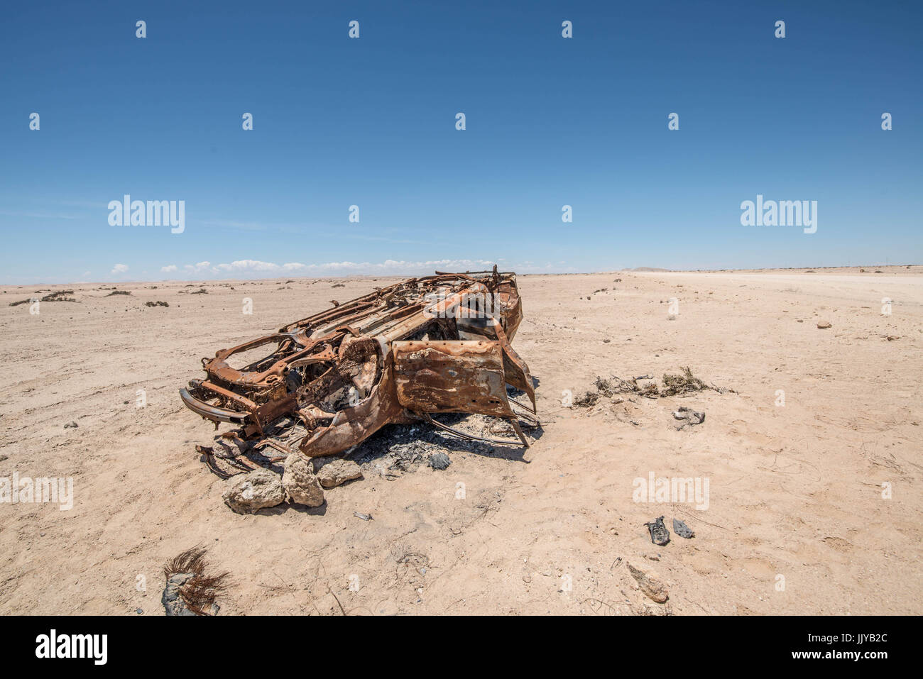 An abandoned, rusted car frame sits in the Namib desert, located in ...