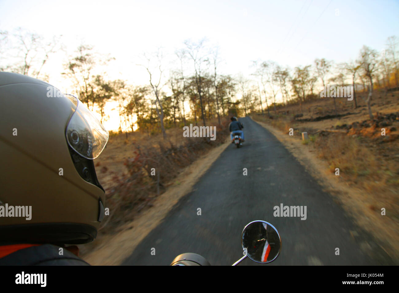 Biker driving a motorcycle rides along the asphalt road Stock Photo - Alamy