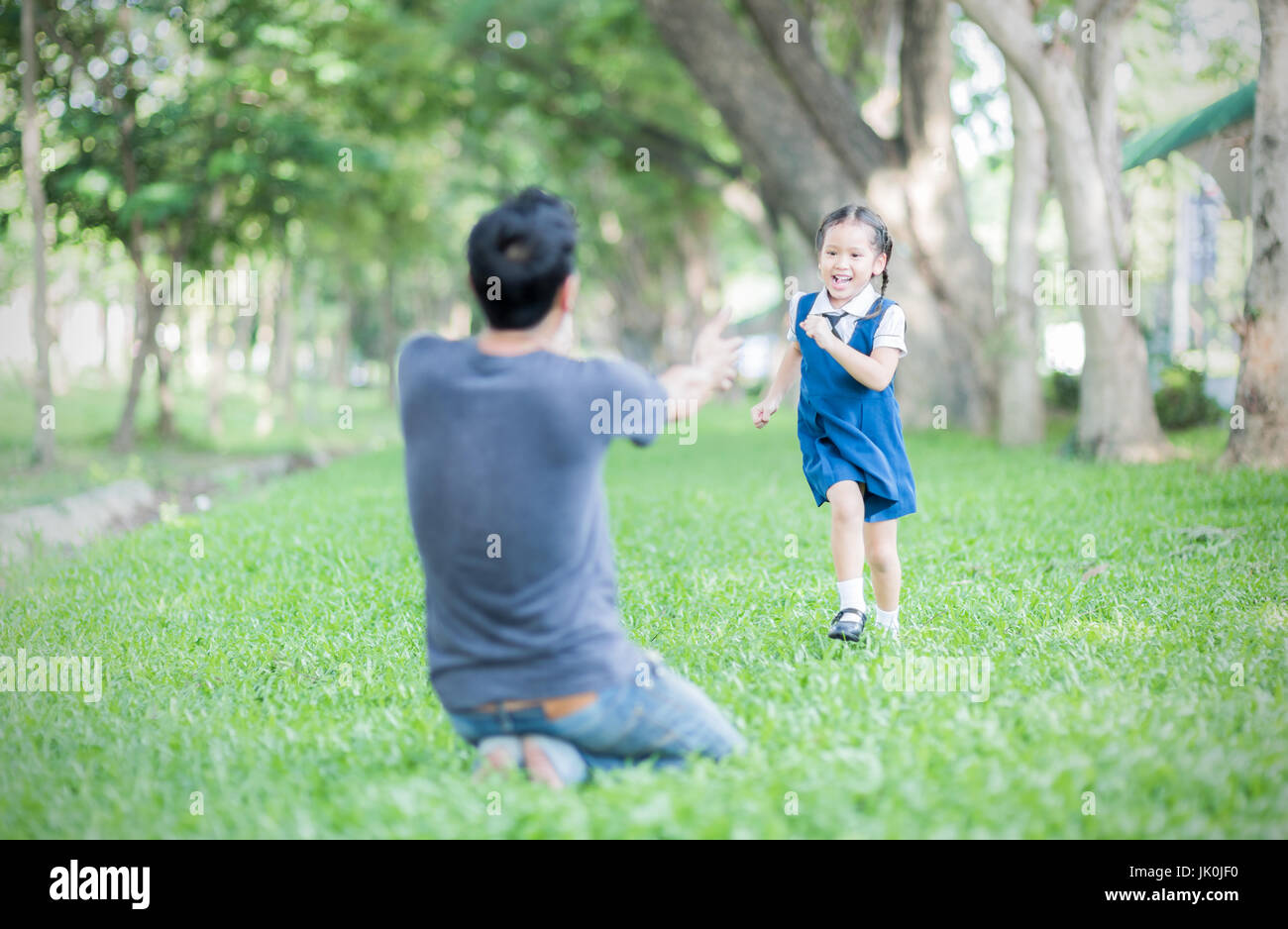 Kids student in uniform running into father's hands to hug her after ...