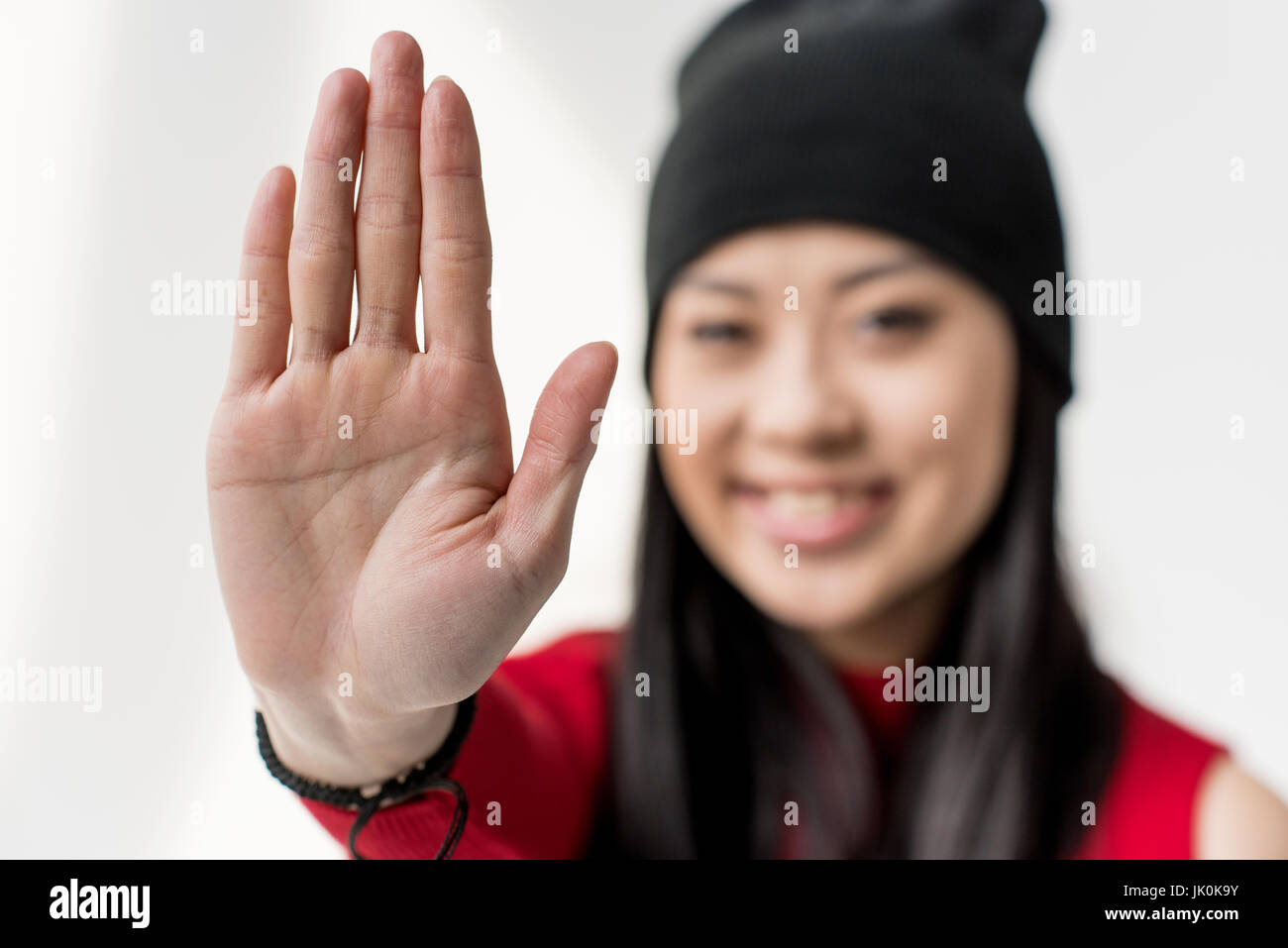 portrait of happy attractive asian woman showing stop sign isolated on ...