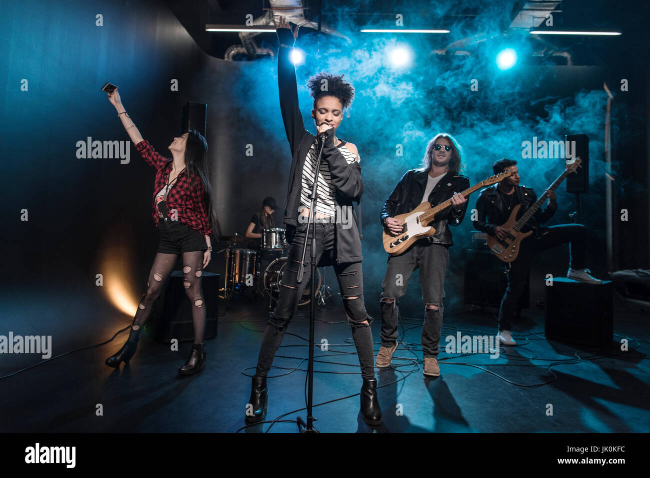 Female singer with microphone and rock and roll band performing hard ...