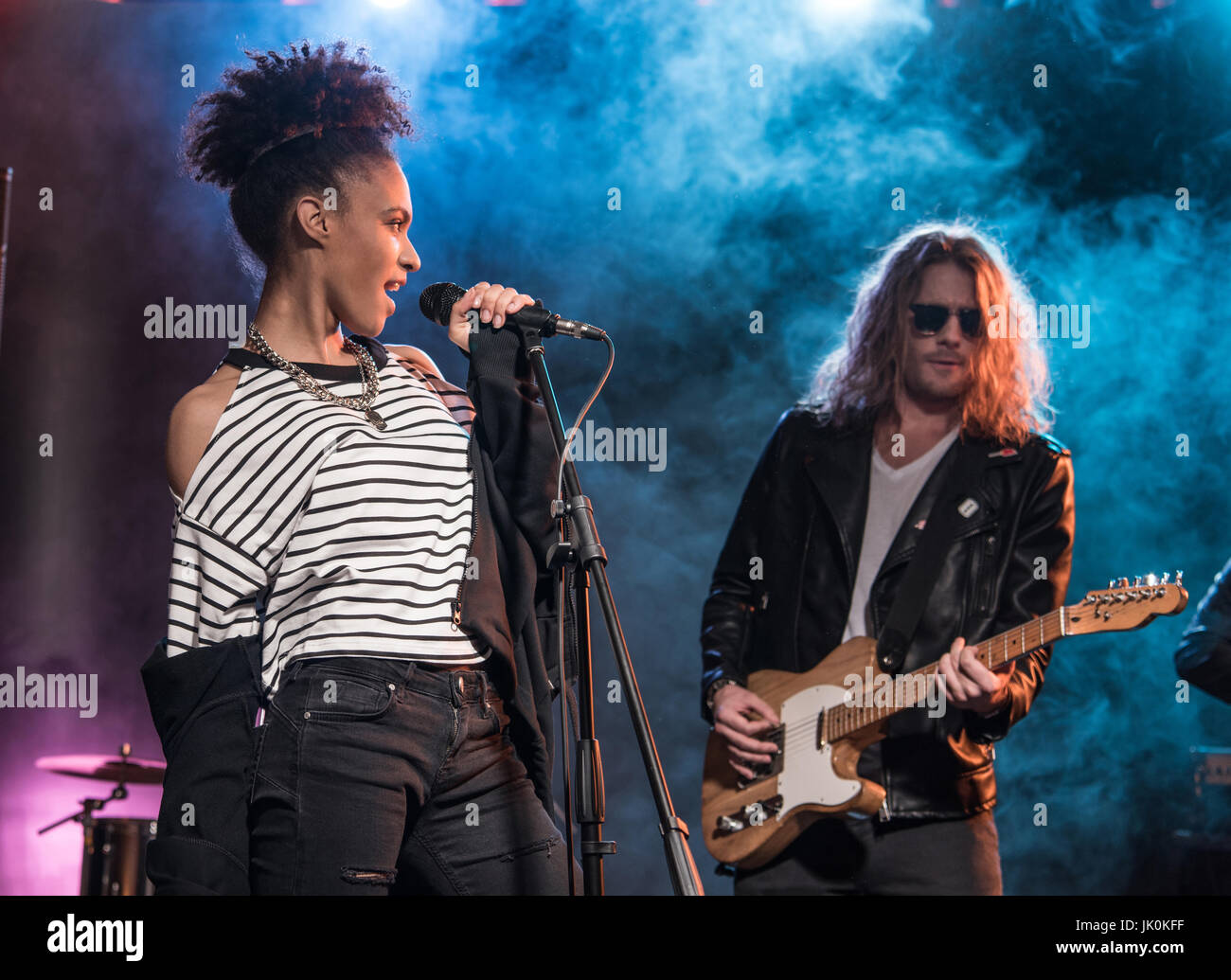 Female singer with microphone and rock and roll band performing hard ...