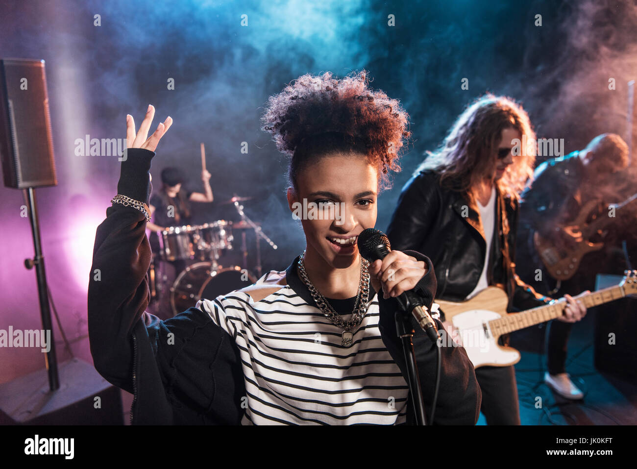 Female singer with microphone and rock and roll band performing hard ...