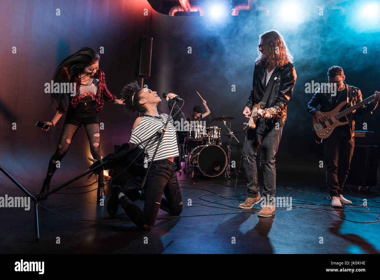 Female singer with microphone and rock and roll band playing hard rock ...