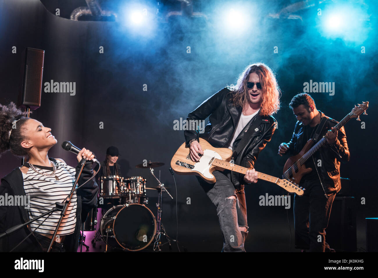 Singer with microphone and electric guitar players performing concert ...