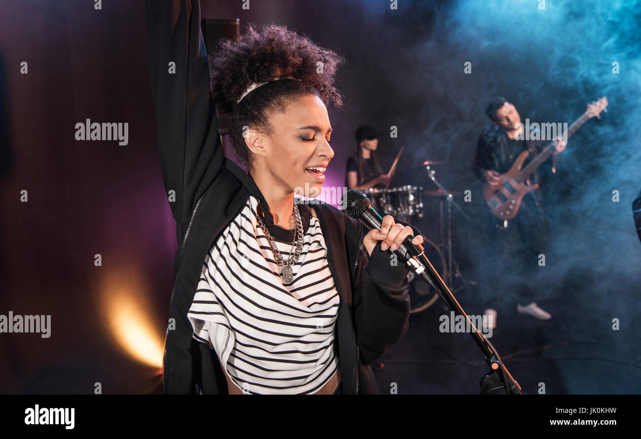 Female singer with microphone and rock and roll band performing hard ...