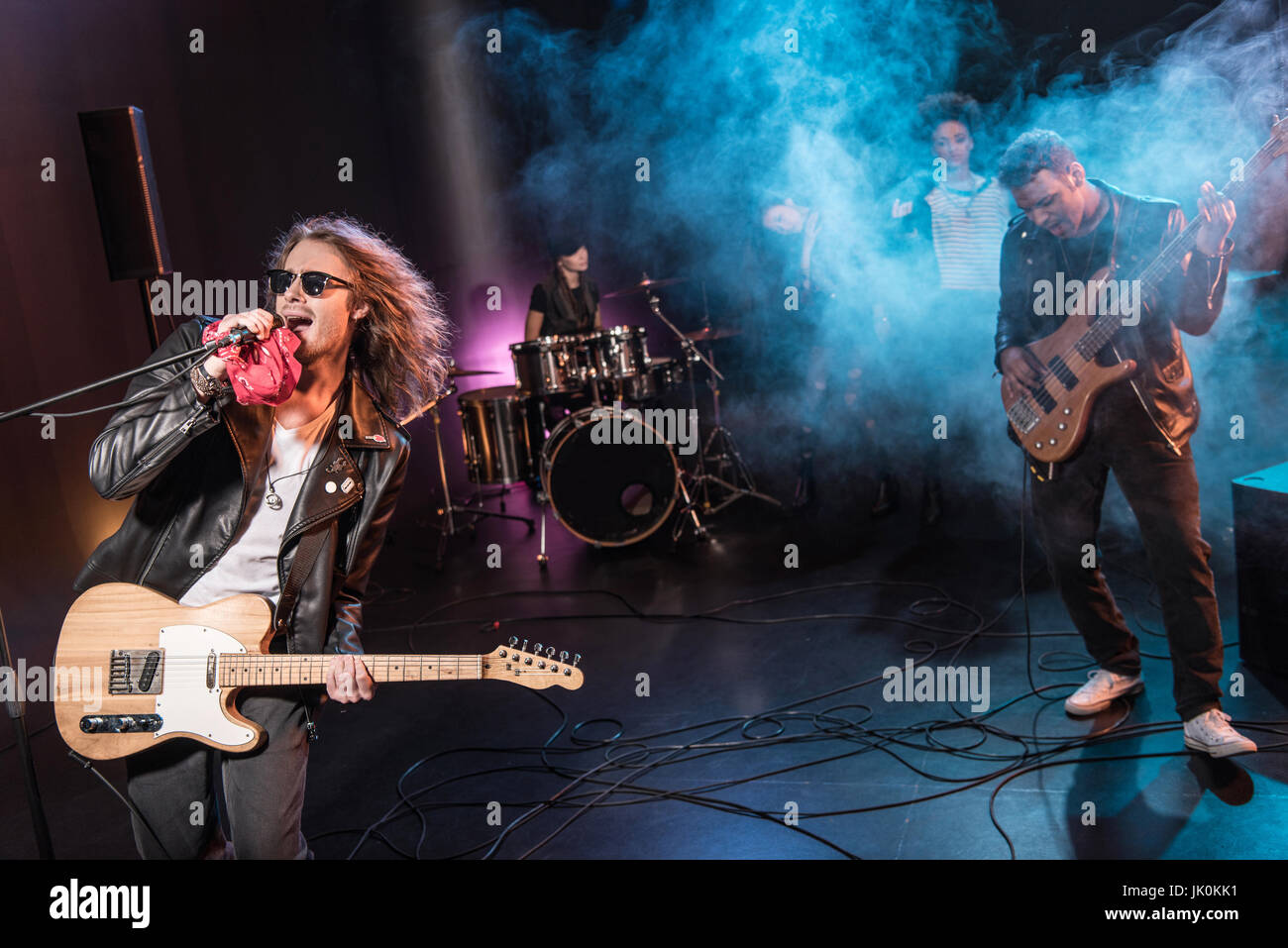 Male singer with microphone and rock and roll band performing hard rock ...