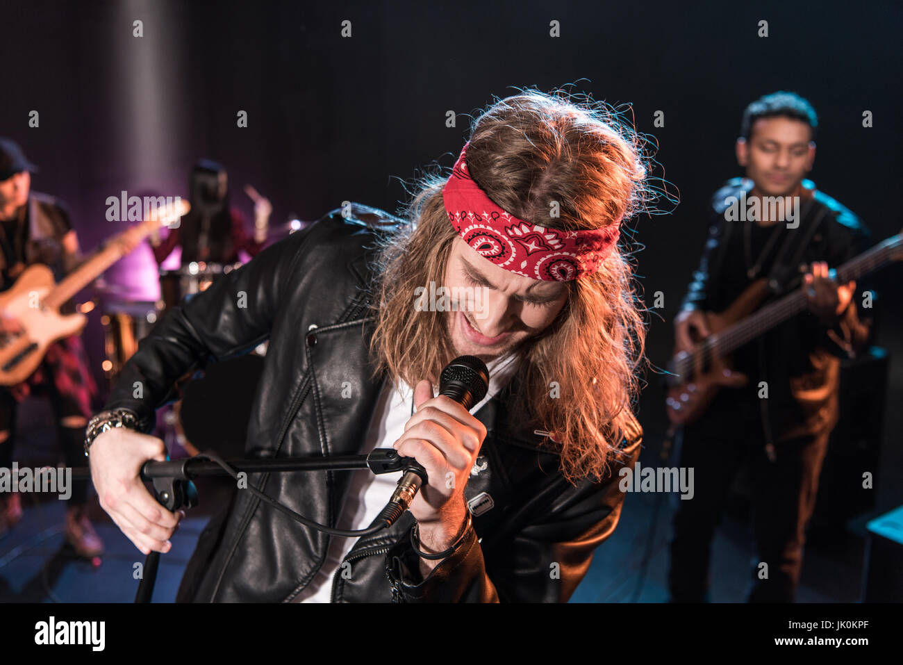 Handsome singer with rock and roll band performing music on stage Stock ...