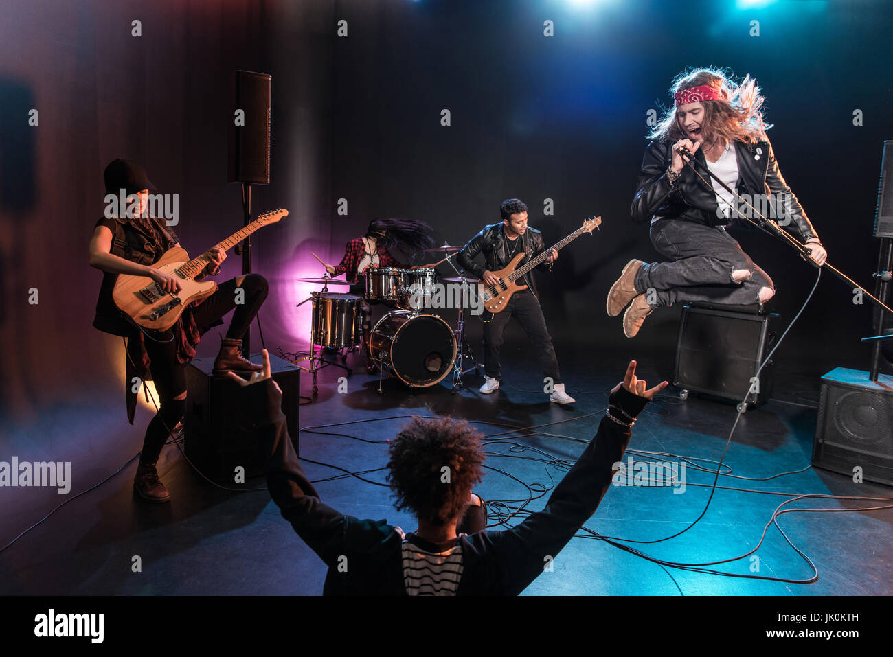 Back view of young woman gesturing rock and roll hand sign and looking ...