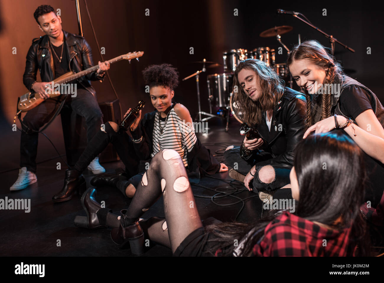 Young rock and roll band sitting together and drinking beer after ...