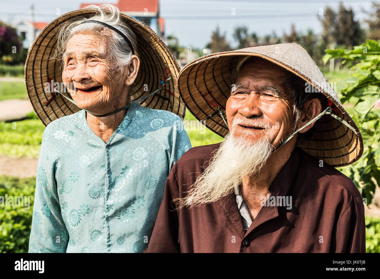 Smiling old Vietnamese couple in traditional dress and conical hats in ...
