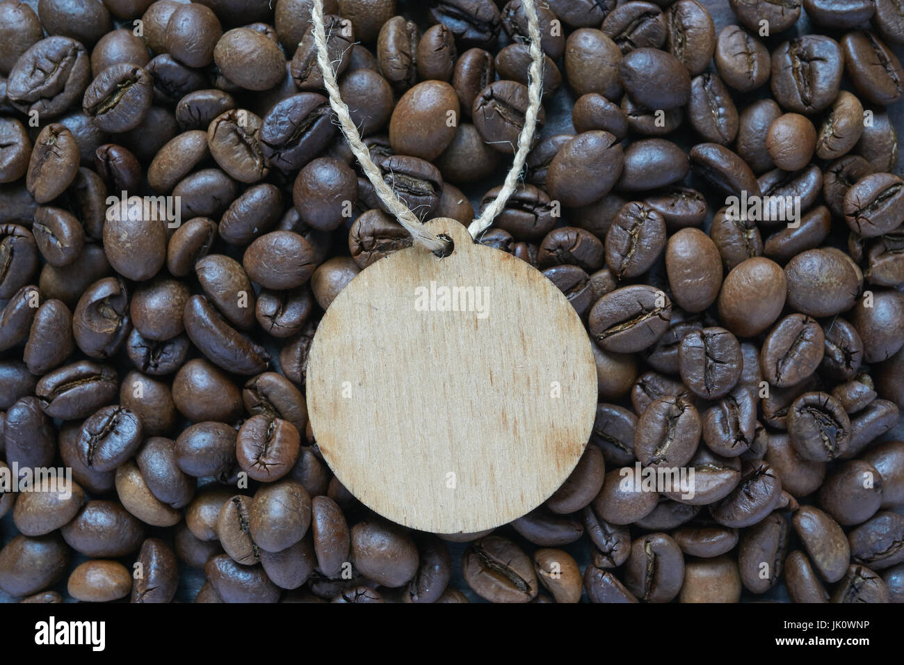 circle wooden tag lay on brown roasted coffee beans. label for ...