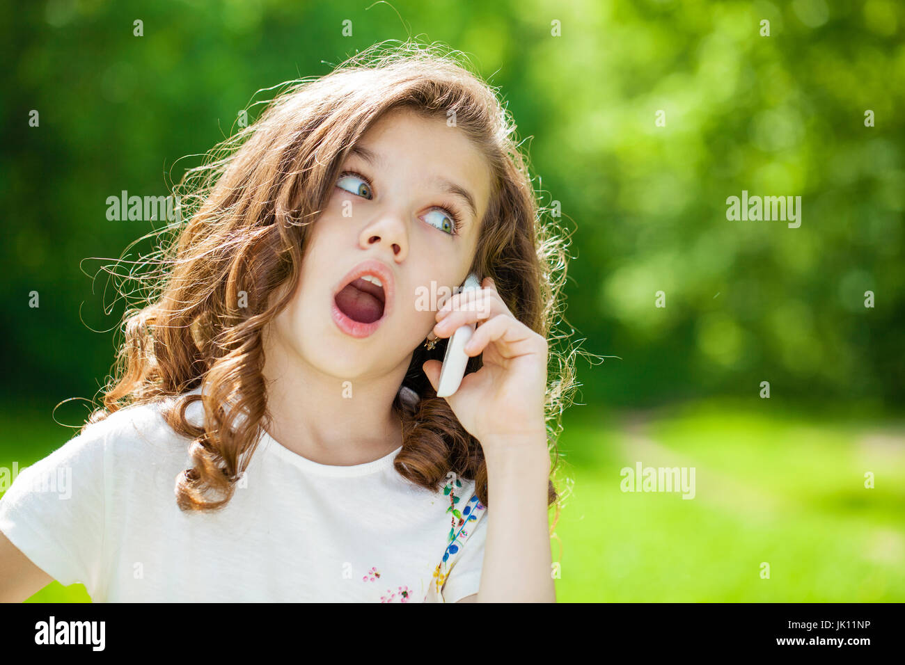 Beautiful little girl calling by mobile phone on the background of ...