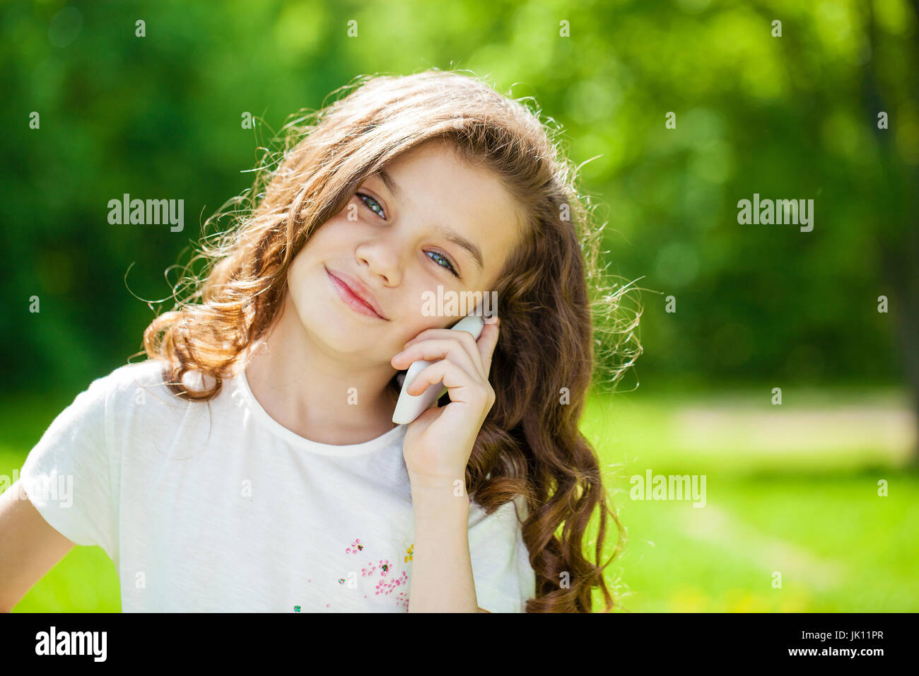 Beautiful little girl calling by mobile phone on the background of ...