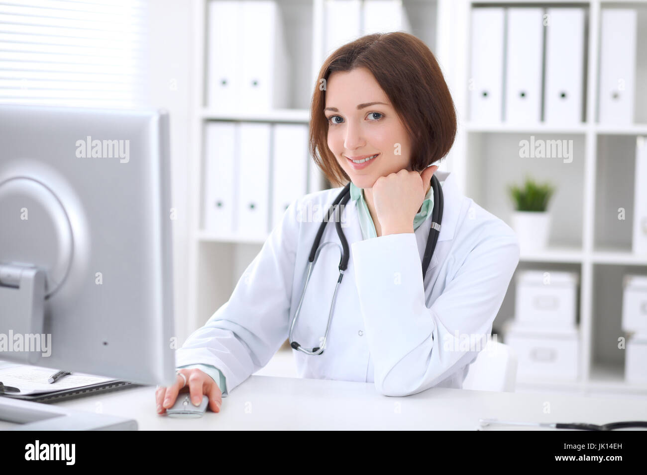 Young brunette female doctor sitting at a desk and working on the ...