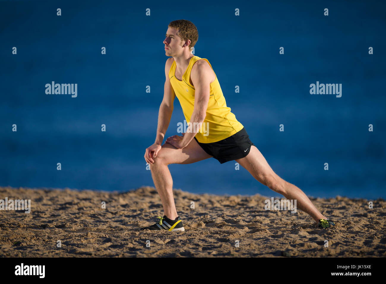 Runner warming up stretching leg muscles Stock Photo - Alamy