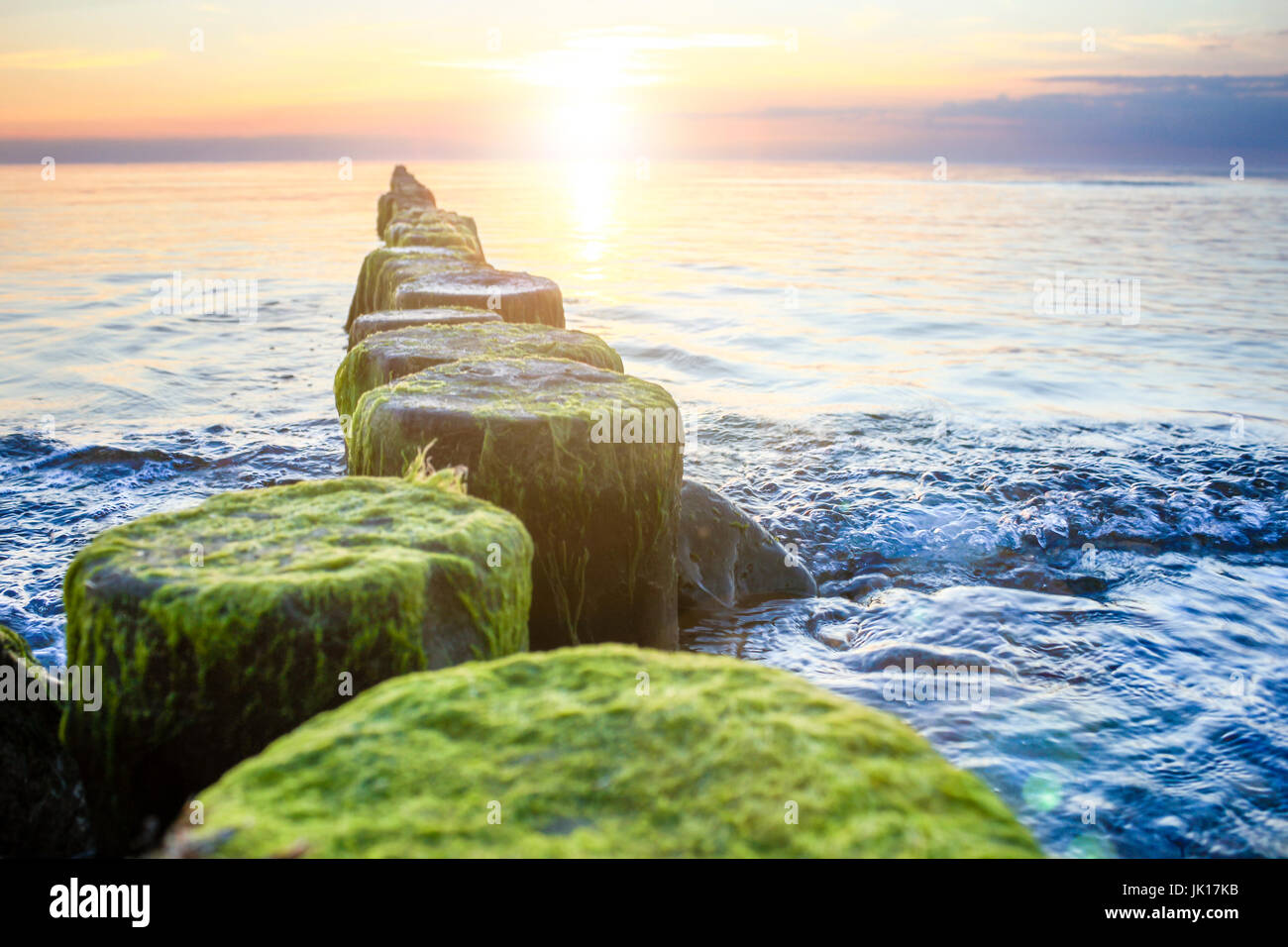 Wooden spur dykes in coastal sunset. Groynes and sea water Stock Photo ...