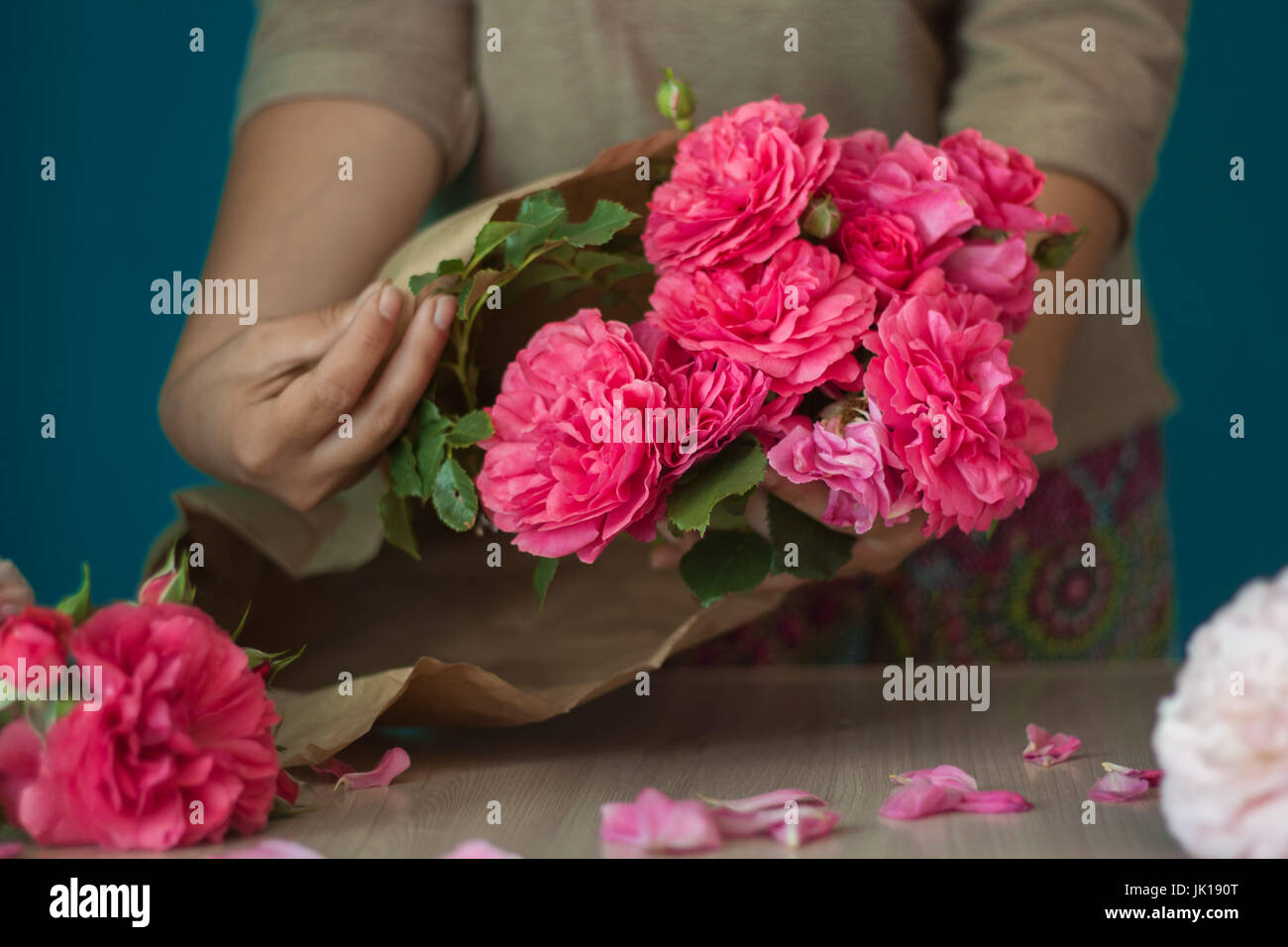 girl florist wraps beautiful pink roses in paper Stock Photo - Alamy