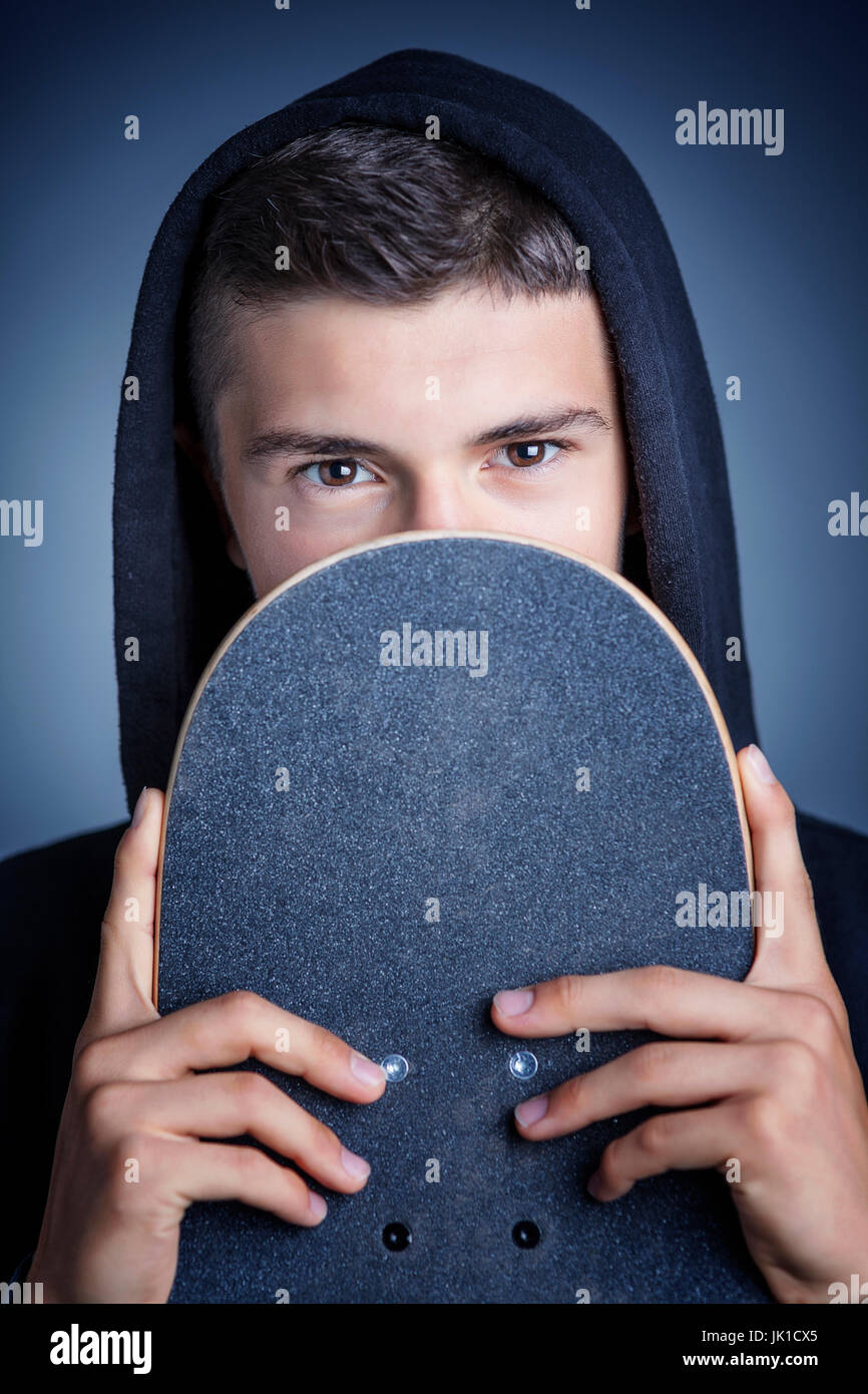 portrait of caucasian boy hide with skateboard studio shot Stock Photo ...