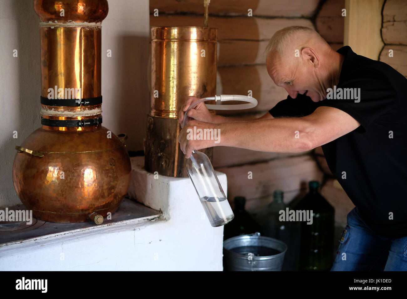 A Russian man fills up a bottle of Samogon distilled alcoholic beverage ...