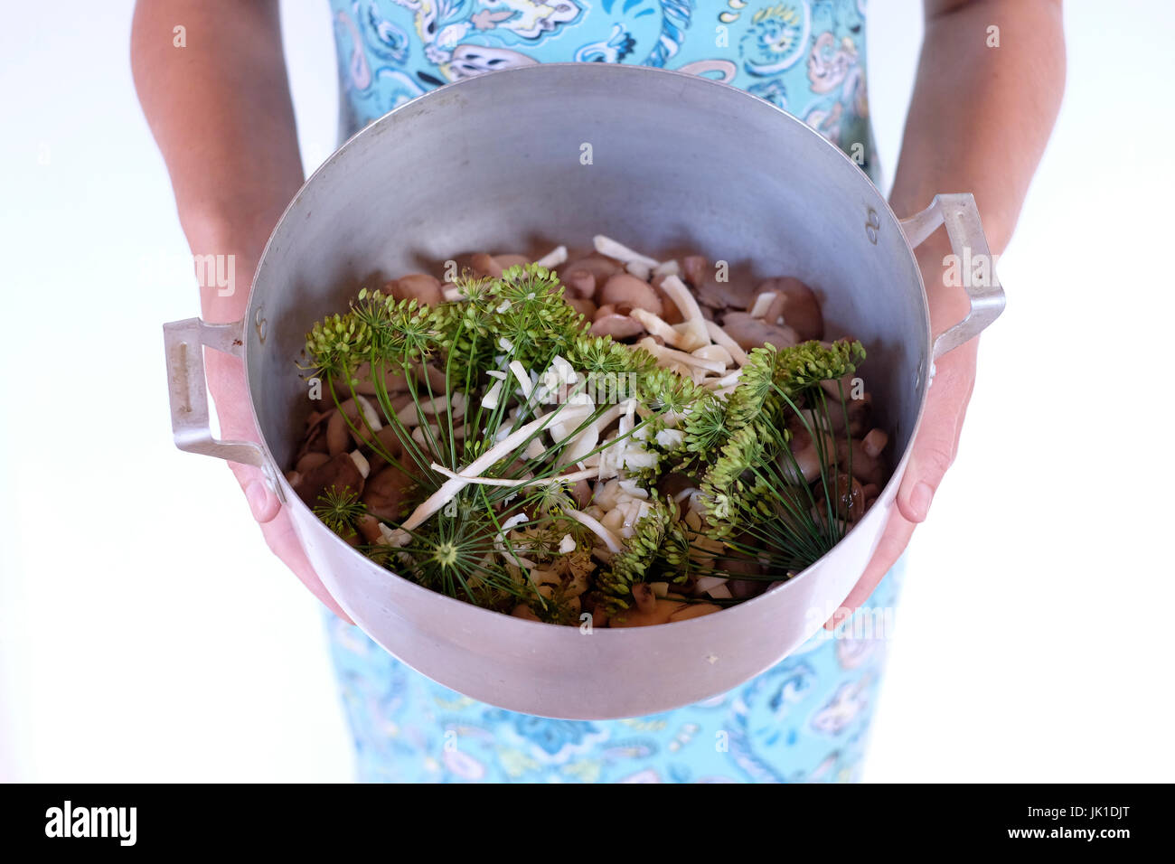 A Russian villager holds a cooking pot filled with fresh herbs and ...
