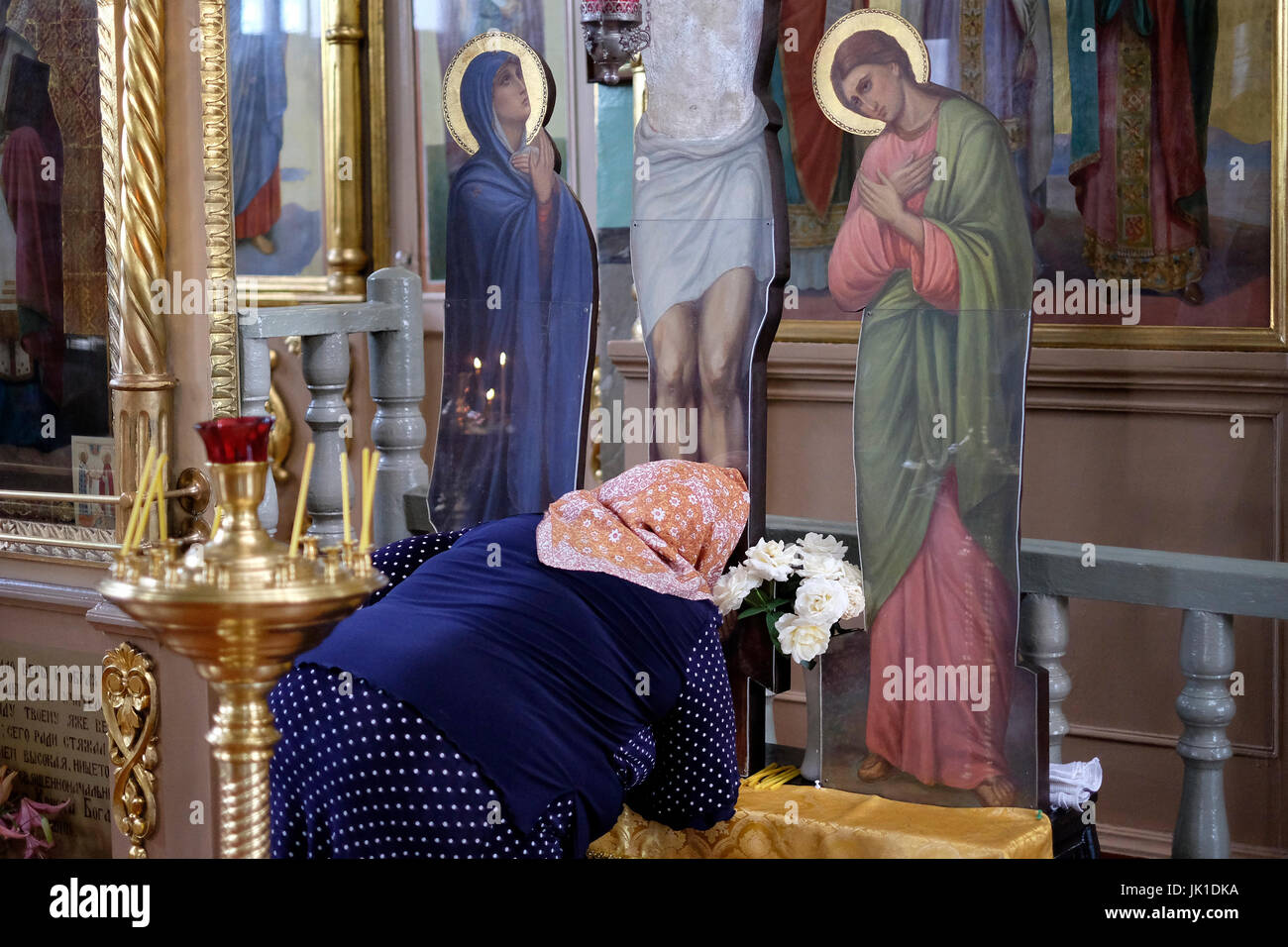 An elderly Russian Orthodox woman praying inside Uspenskiy Sobor church ...