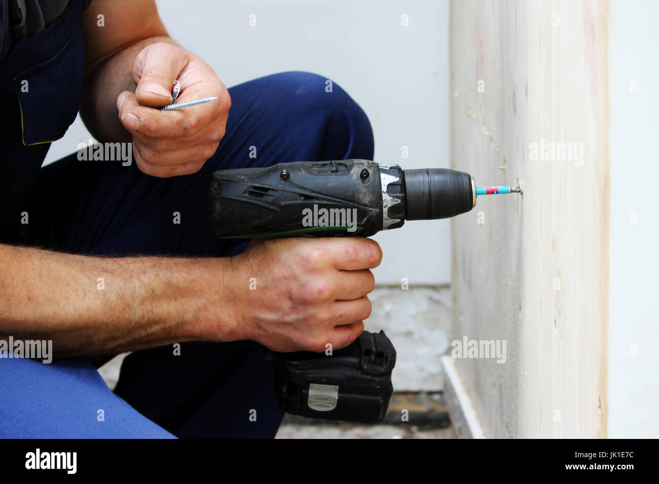 The worker screws screw with a screwdriver while decorating the window ...