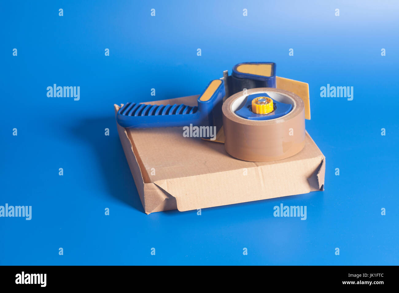 Dispenser with cardboard box on blue background Stock Photo - Alamy