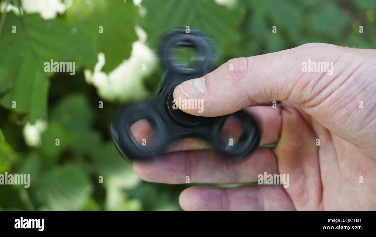Playing with the black Fidget Spinner. Toy spinner in hand Stock Photo ...