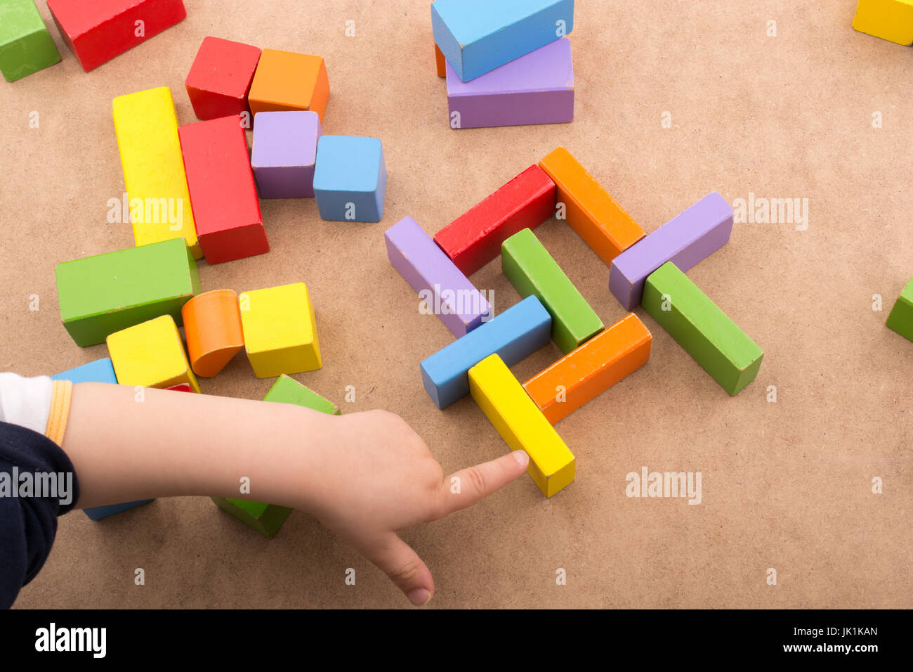 Toddler hand over Colorful building blocks on brown background Stock ...