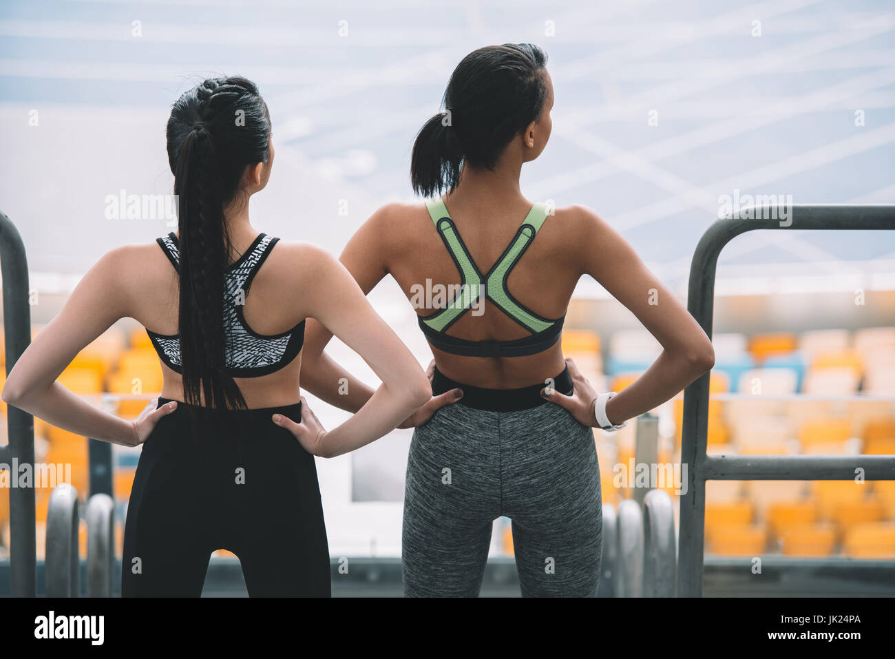 rear view of two young sportswomen standing on stadium ready for ...