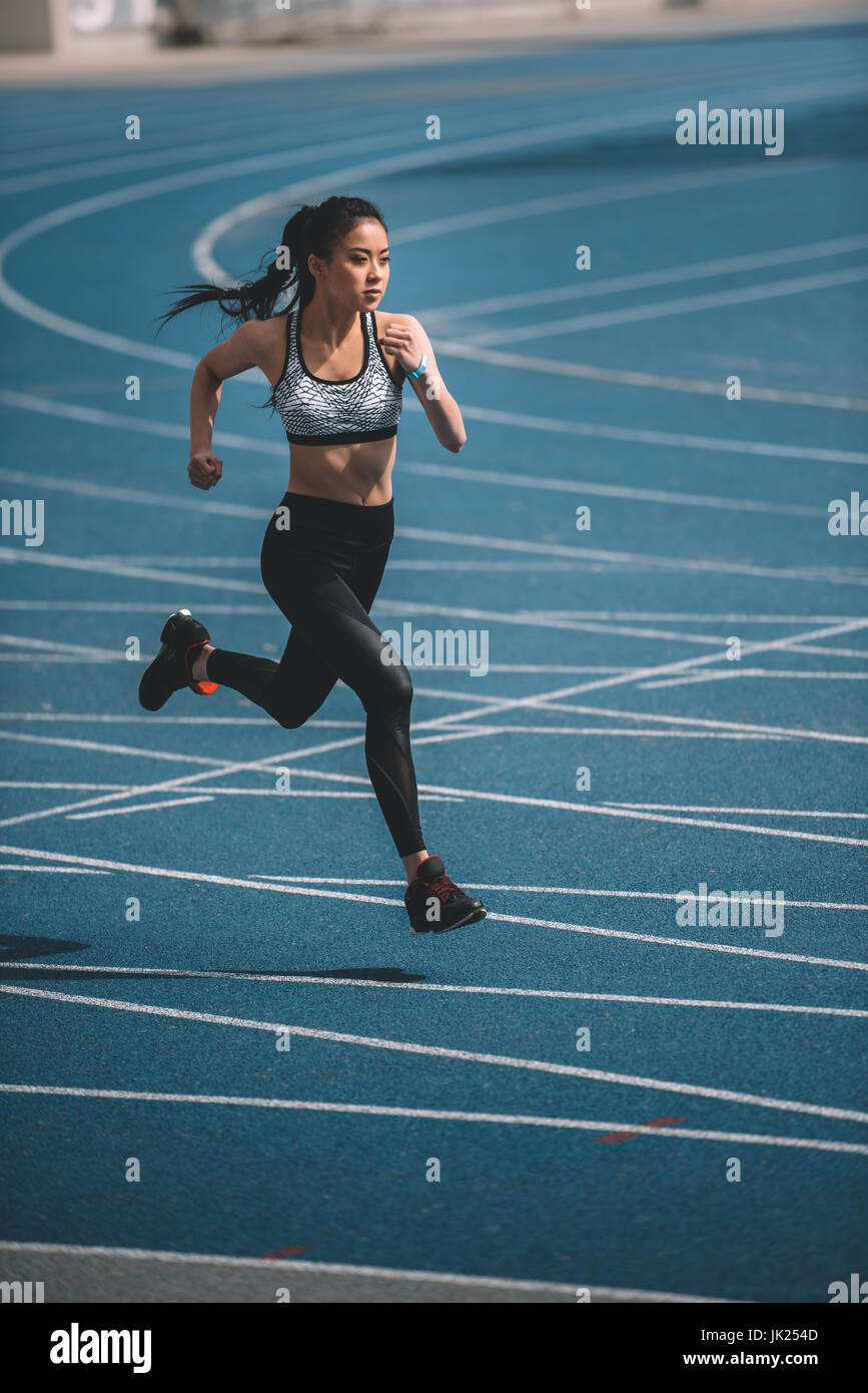 Athletic young sportswoman sprinting on running track stadium Stock ...